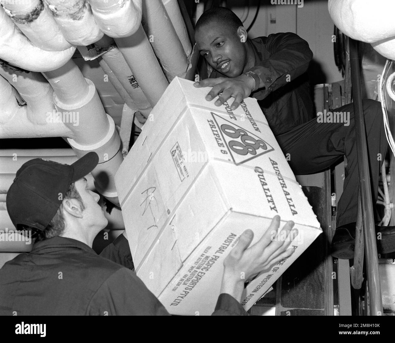 Sailors remove boxes of food from a storage compartment in preparation ...