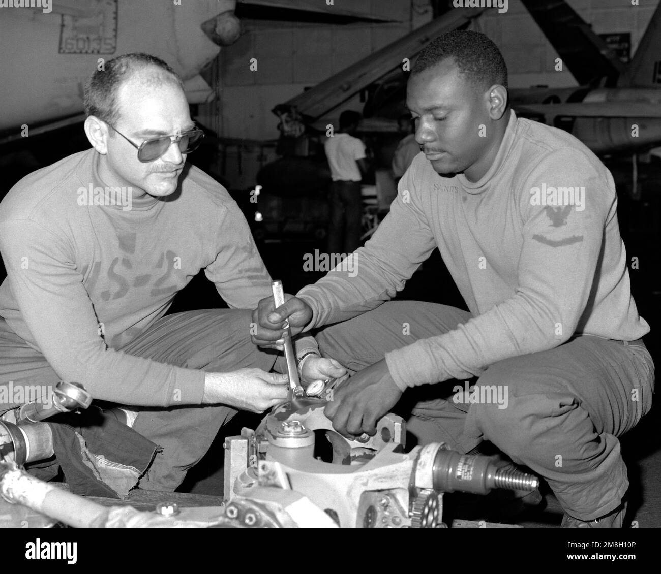 Crew members service a motor valve hook-up in the hangar bay of the ...
