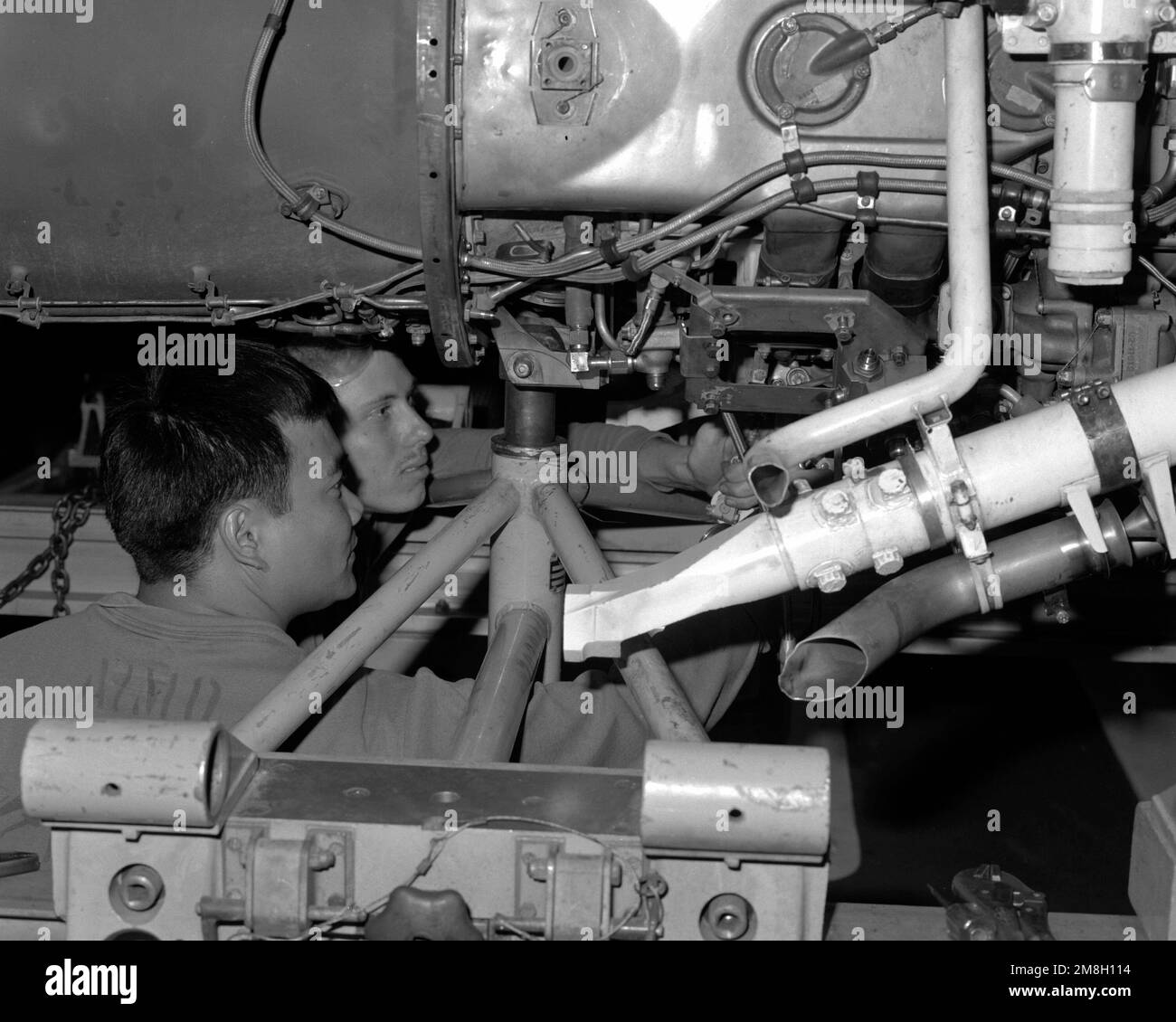 A pair of aviation structural mechanics service an aircraft engine of ...