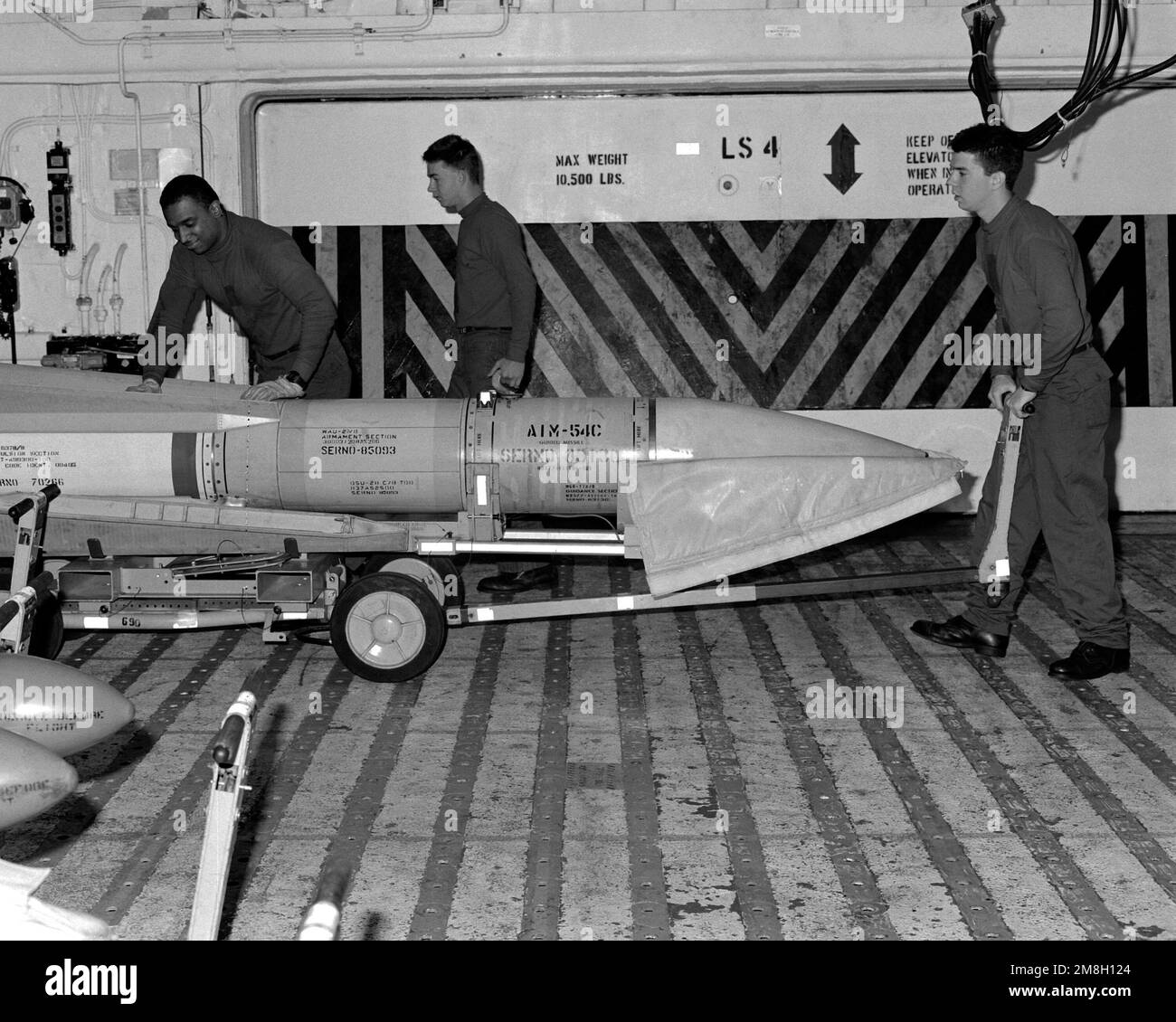 Aviation ordnancemen position an AIM-54C Phoenix missile in a magazine ...