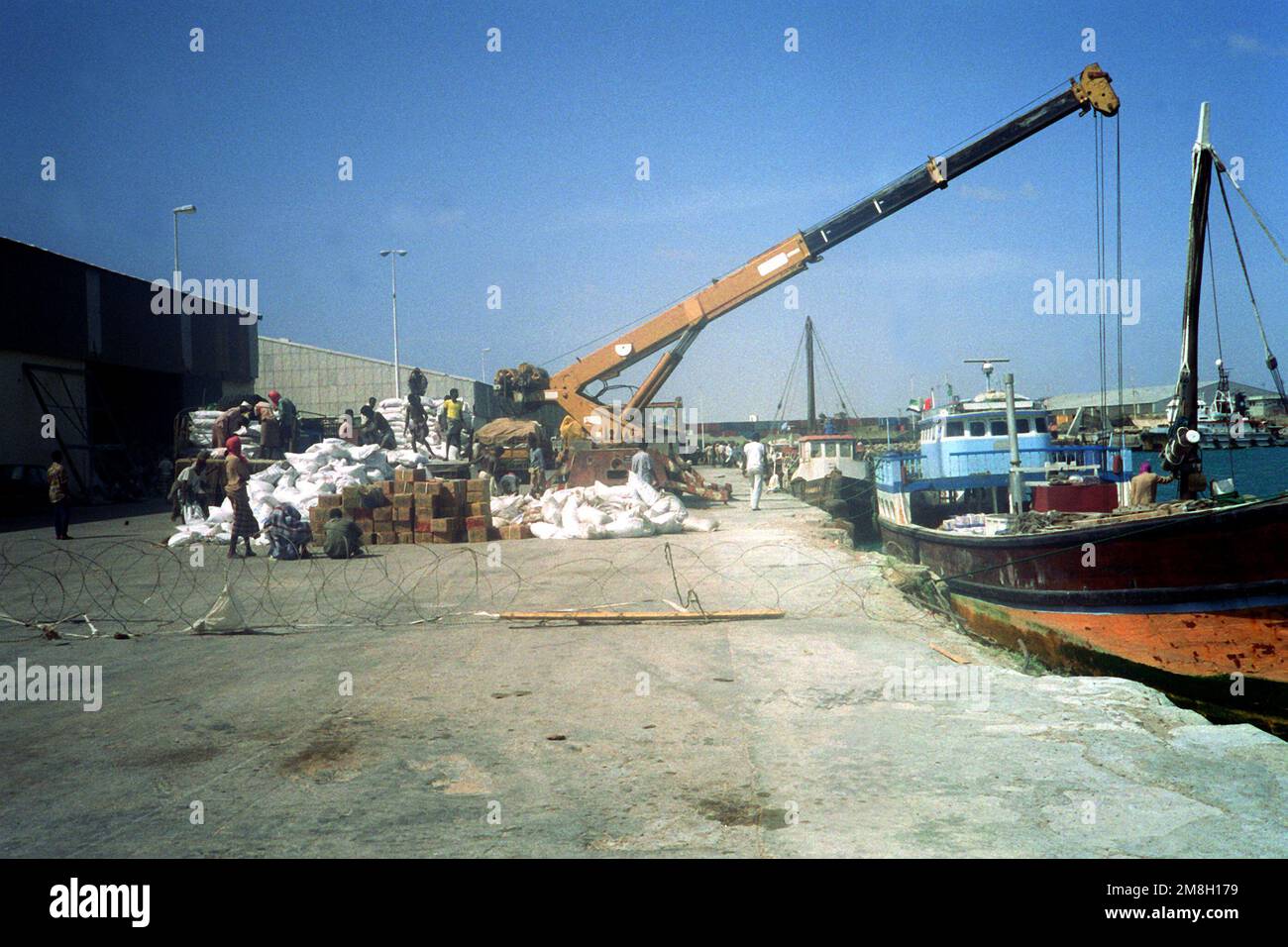 A crane unloads supplies from a boat during Operation Restore Hope ...