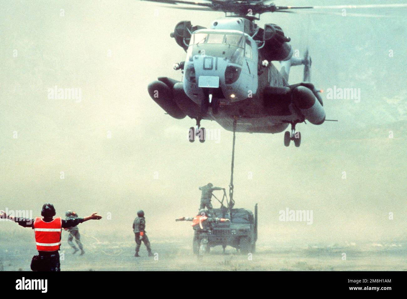 Marines guide a CH-53 Sea Stallion helicopter as it prepares to lift an ...