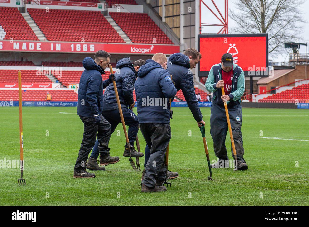 Nottingham Forest groundsmen tend to the pitch after heavy rainfall ...