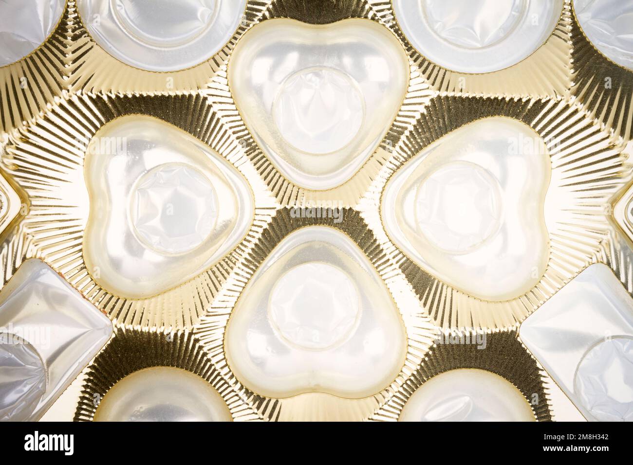 Close up shot of empty box of chocolates. Shiny gold plastic texture of ...