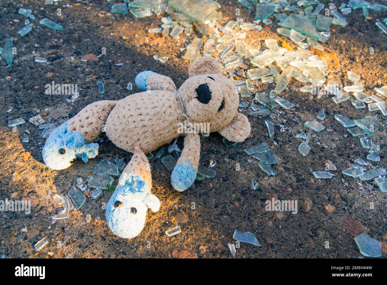 A toy (teddy bear) lies on the sidewalk against the background of ...
