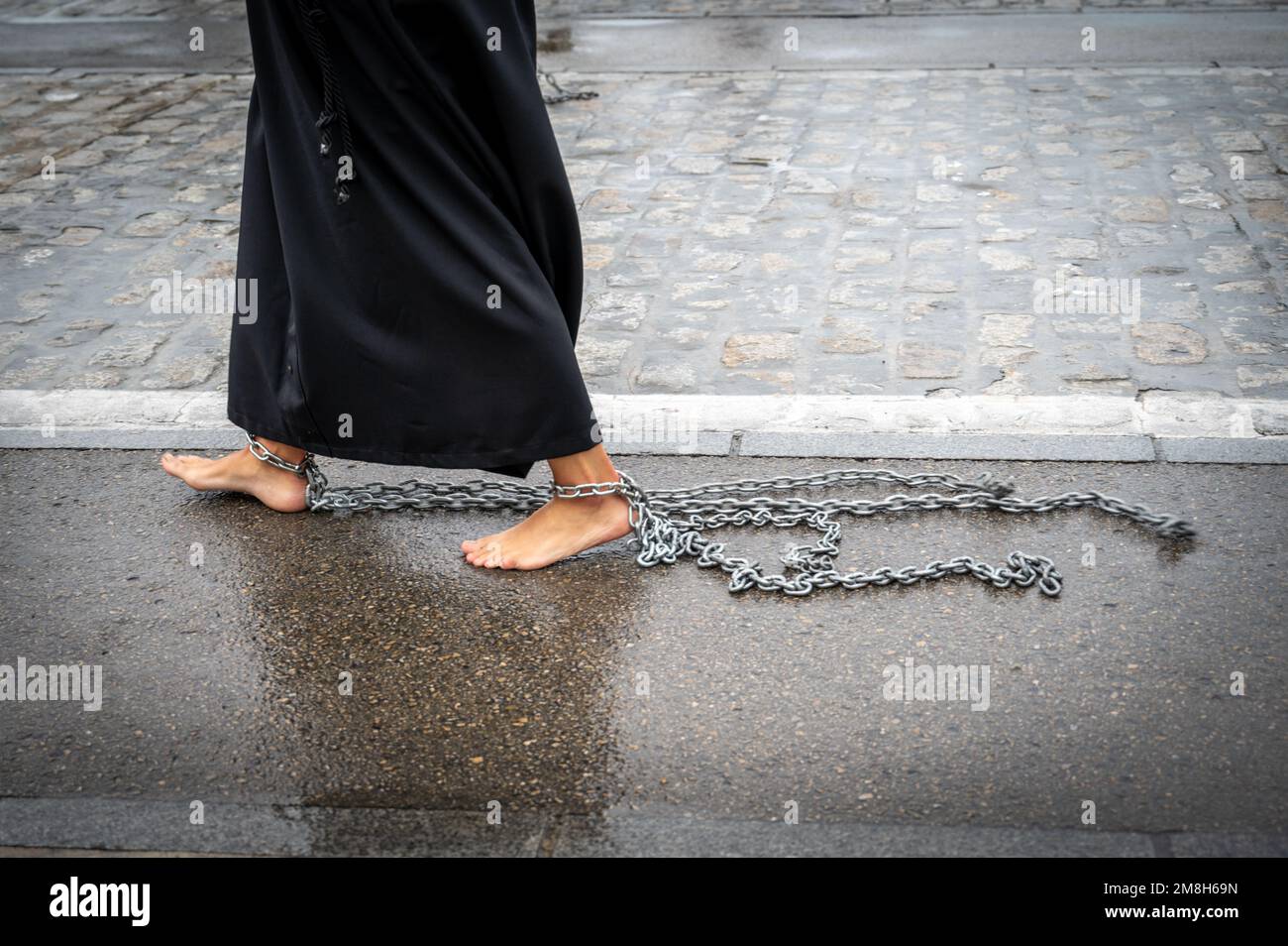 People wearing black clothing and chains walking barefoot in a ...