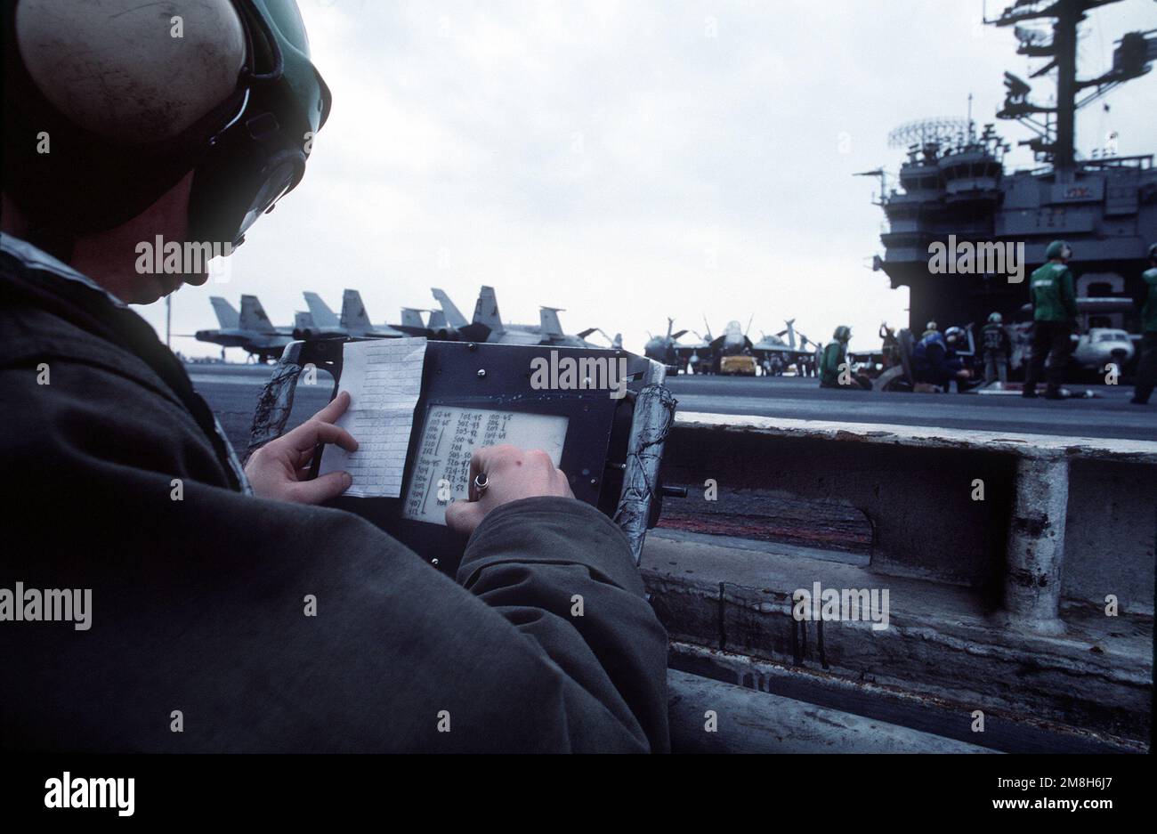 A catapult deckedge operator records flight operations information ...