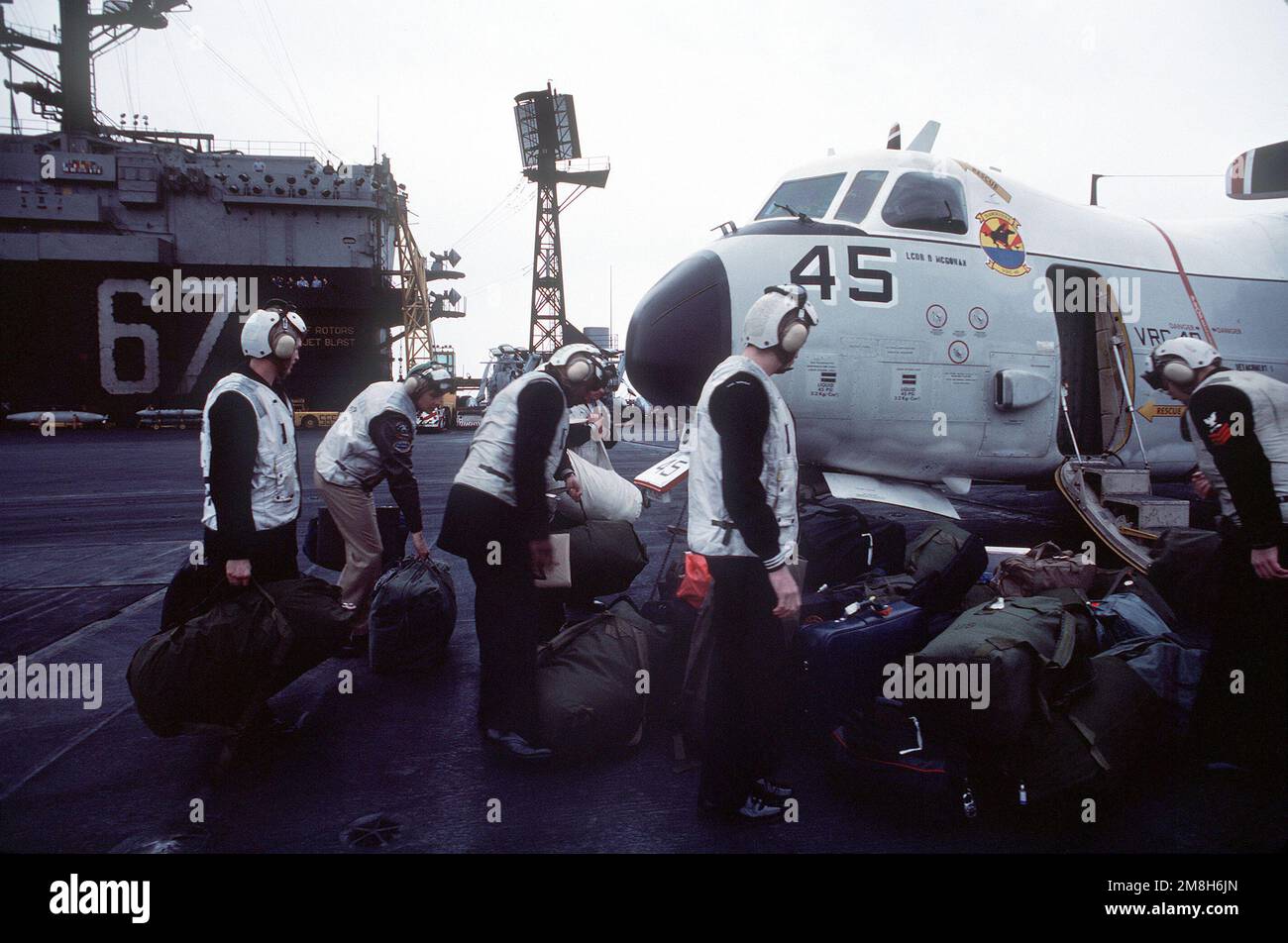 Passengers stage their gear in front of a Fleet Logistic Support ...