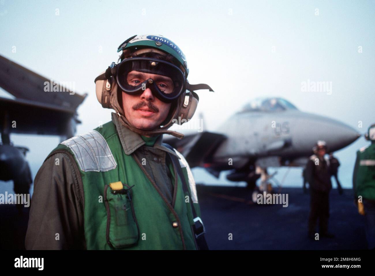 A flight deck crewmen poses for a photograph during a lull in flight ...