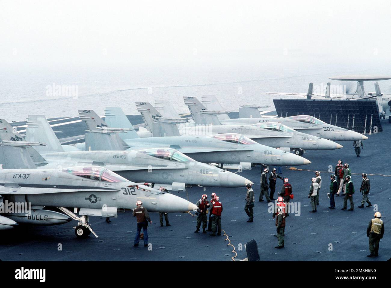 Flight deck crewmen inspect a Strike Fighter Squadron 37 (VFA-37) F/A ...