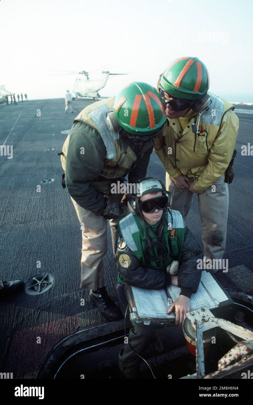 Members of a catapult crew review launch information during flight ...