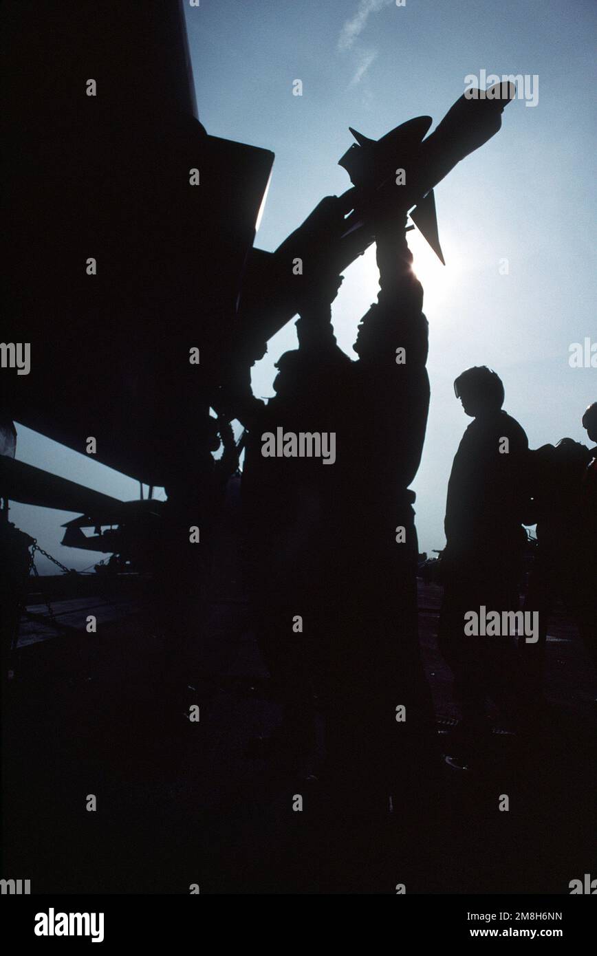 Aviation ordnancemen mount an AIM-9 Sidewinder air-to-air missile on an ...