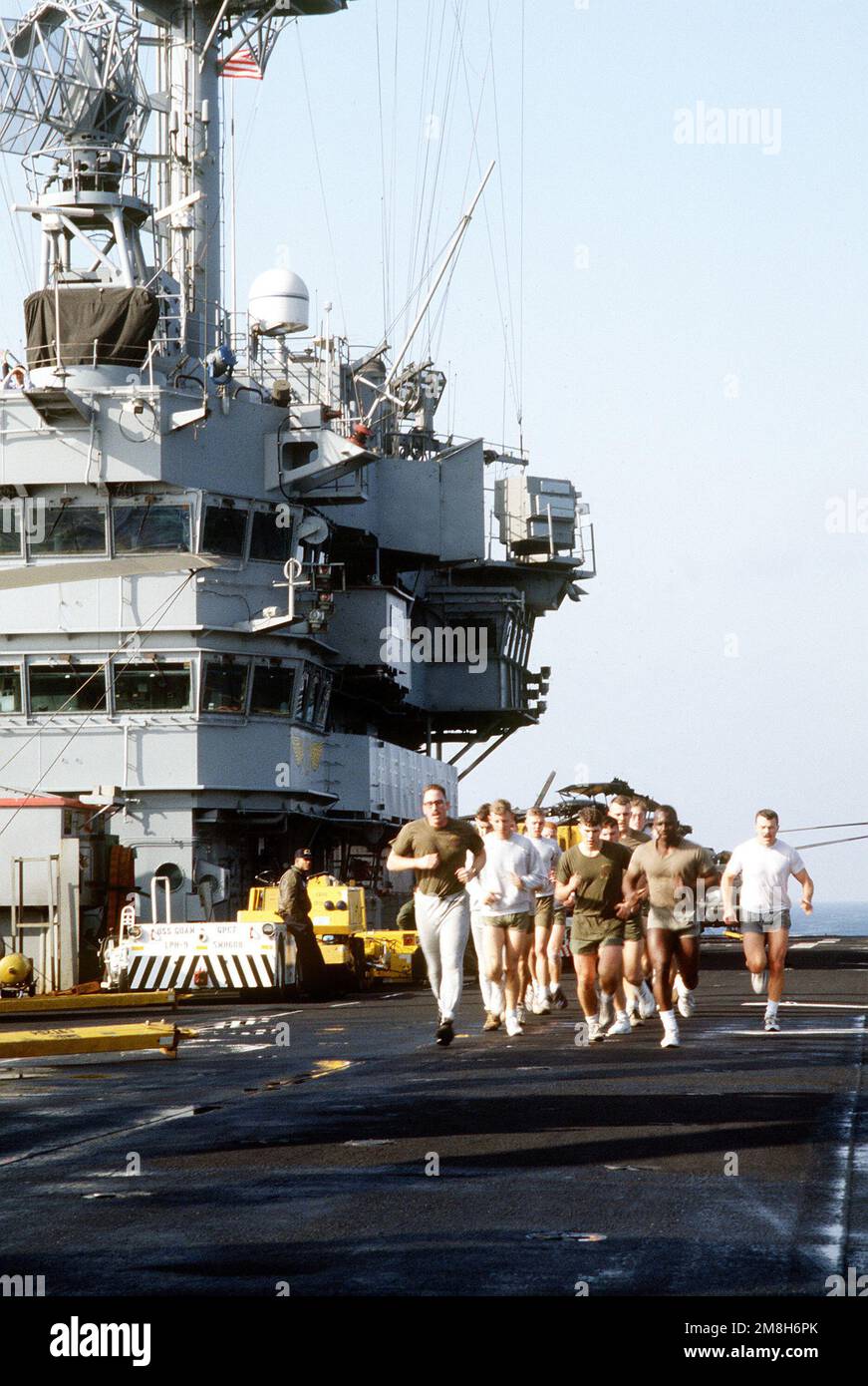 Marines run on the flight deck of the amphibious assault ship USS GUAM ...