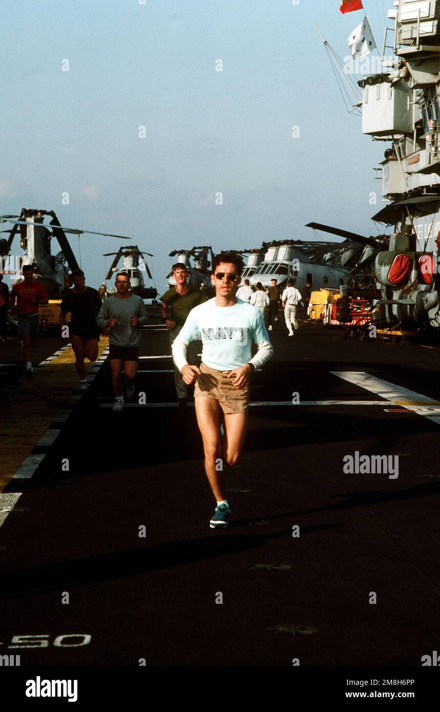 Crewmen and Marines run on the flight deck of the amphibious assault ...