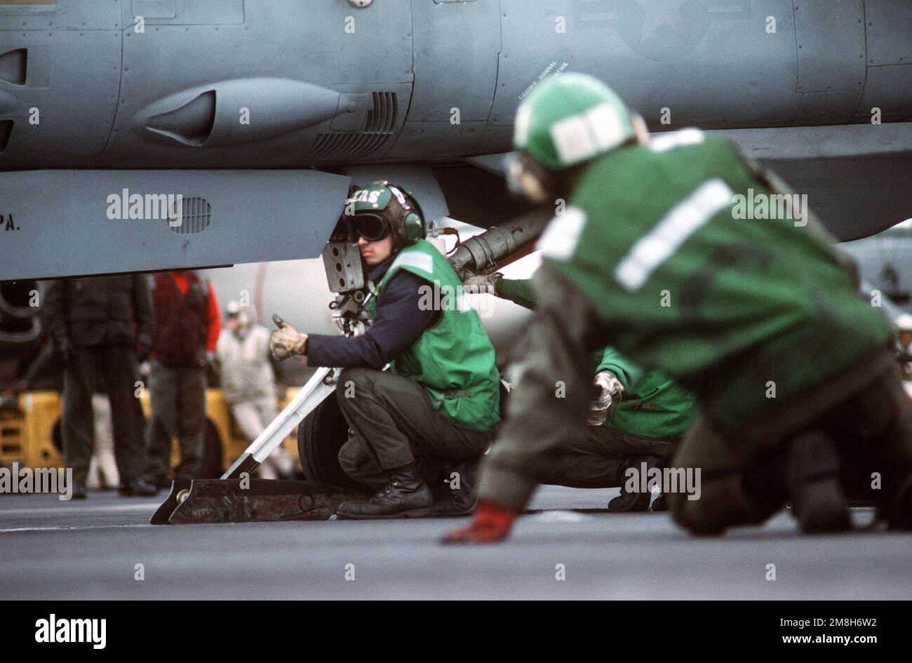The holdback/hookup crew signals to the catapult officer as the ...