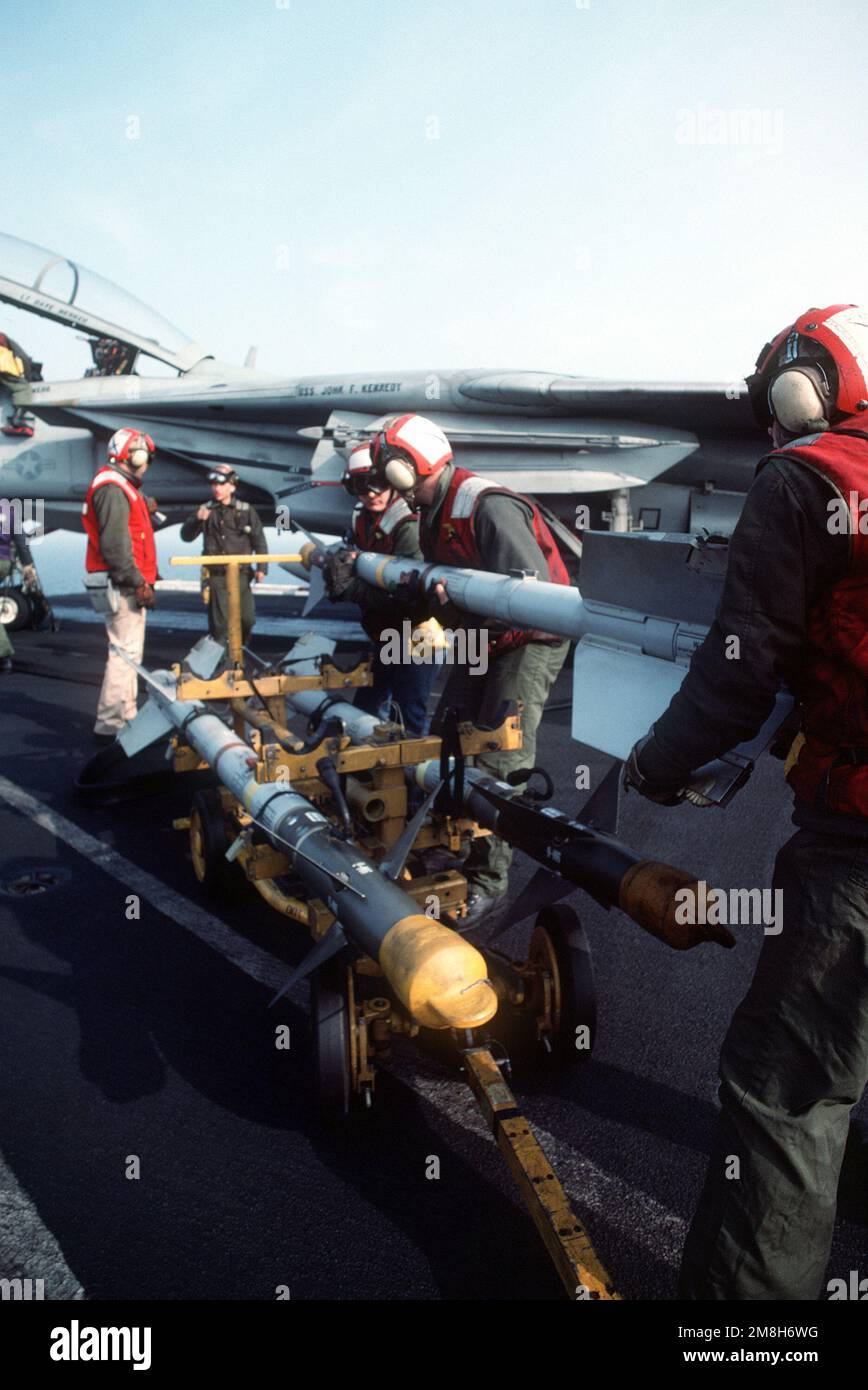 Aviation ordnancemen move an AIM-9 Sidewinder air-to-air missile from a ...