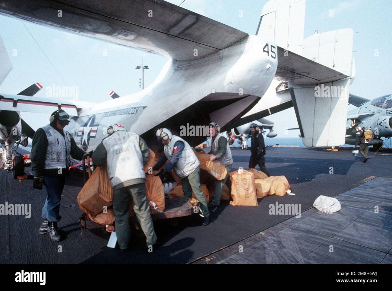 Flight deck crewmen unload bags of mail from a Fleet Logistic Support ...