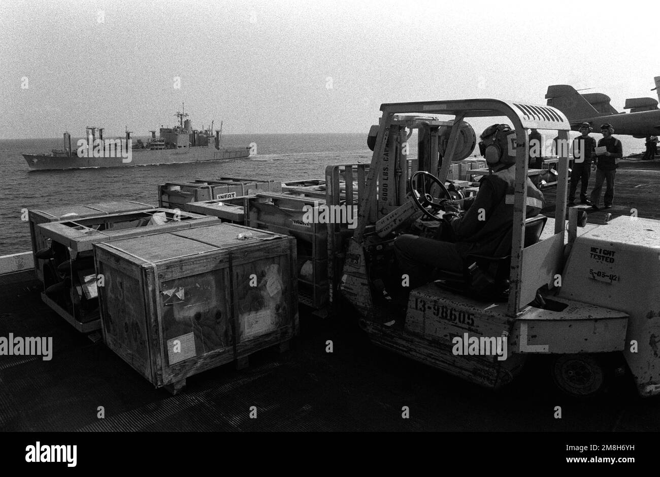 A crew member uses a forklift to move crates of bomb tail assemblies ...