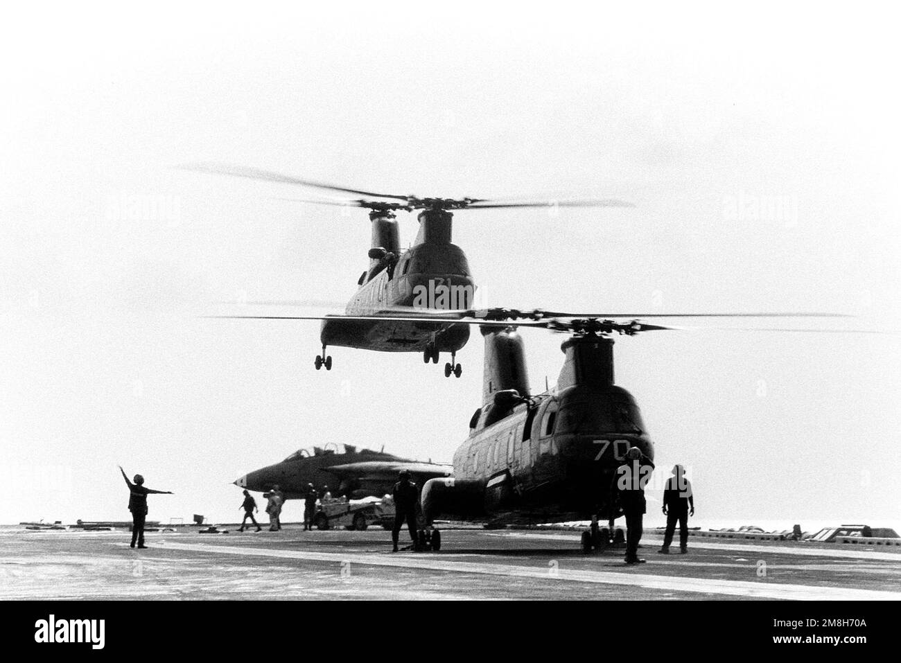 An HH-46 Sea Knight helicopter takes off as another stands on the ...