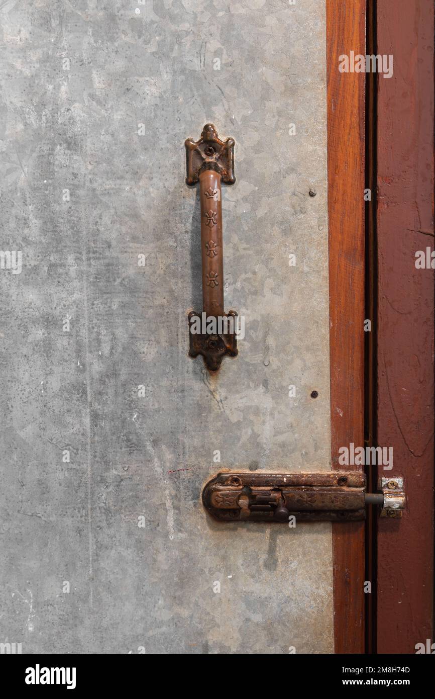 Rusty old door handle and latch on the worn sheet metal door, close up ...