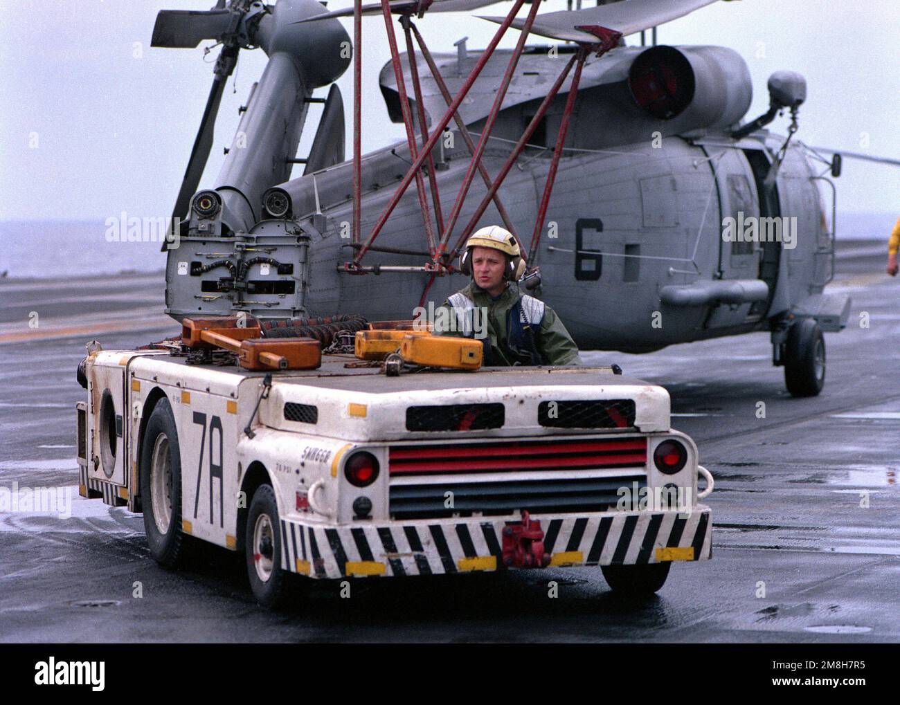 A flight deck crewmen uses an MD-3 tow tractor to spot a Helicopter ...