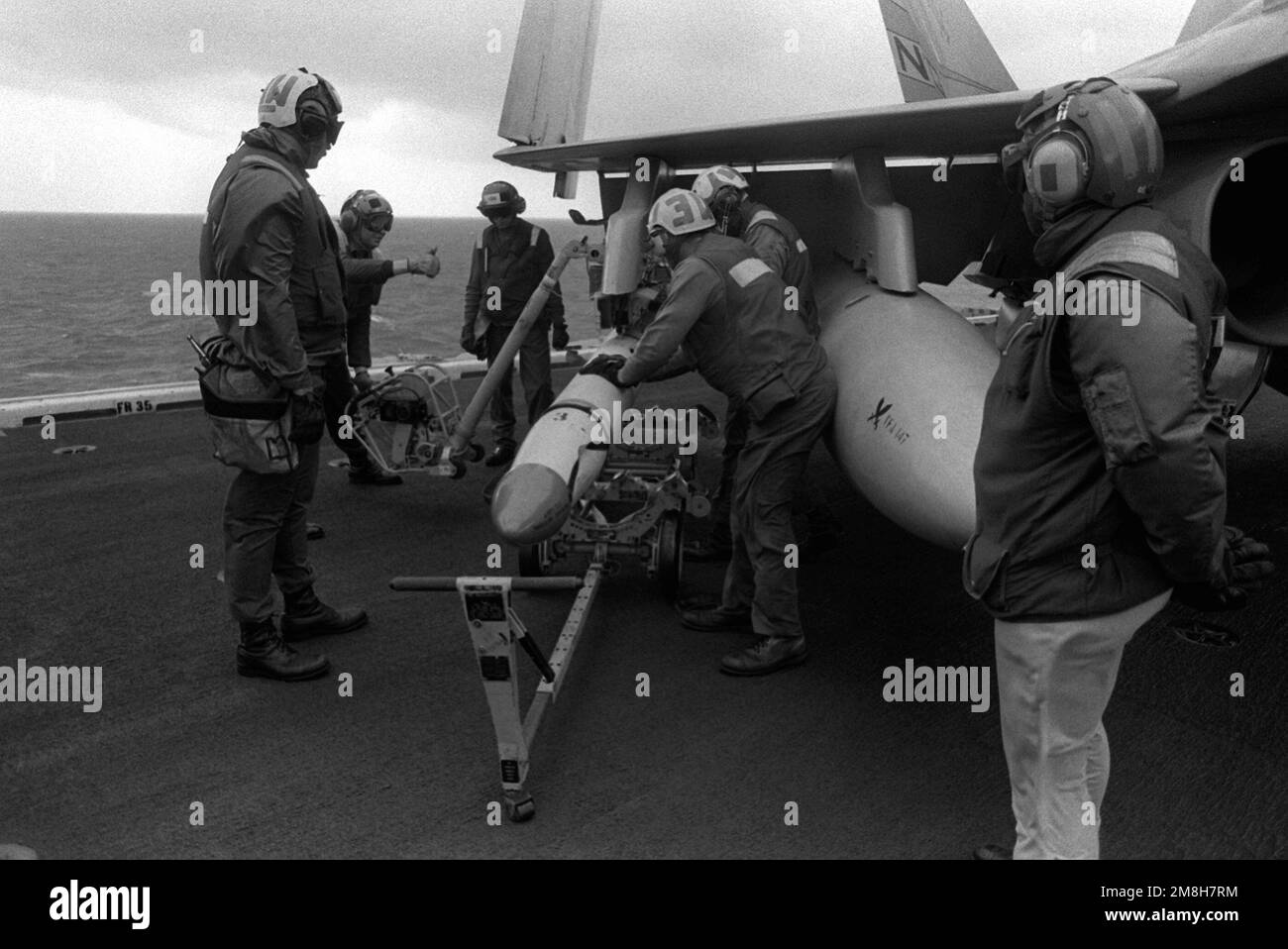 Aviation ordnancemen use an HLU-196A/E bomb hoist to lift an AGM-88 ...