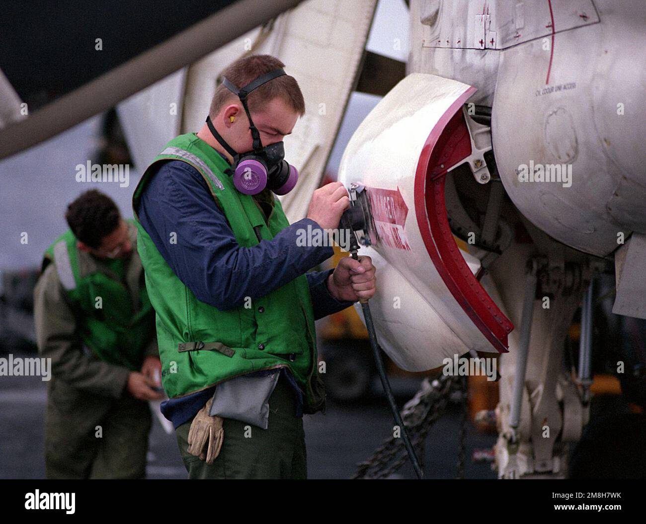 A crew member uses a palm sander while performing corrosion control ...