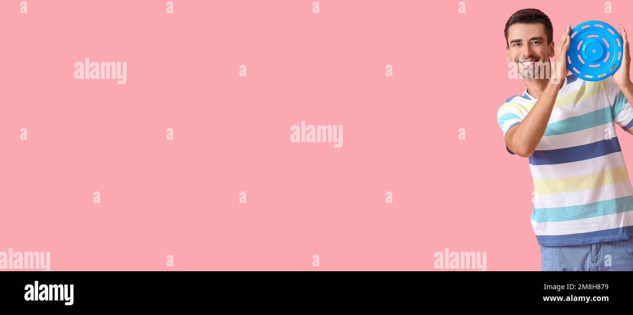 Handsome young man with frisbee disk on pink background with space for ...