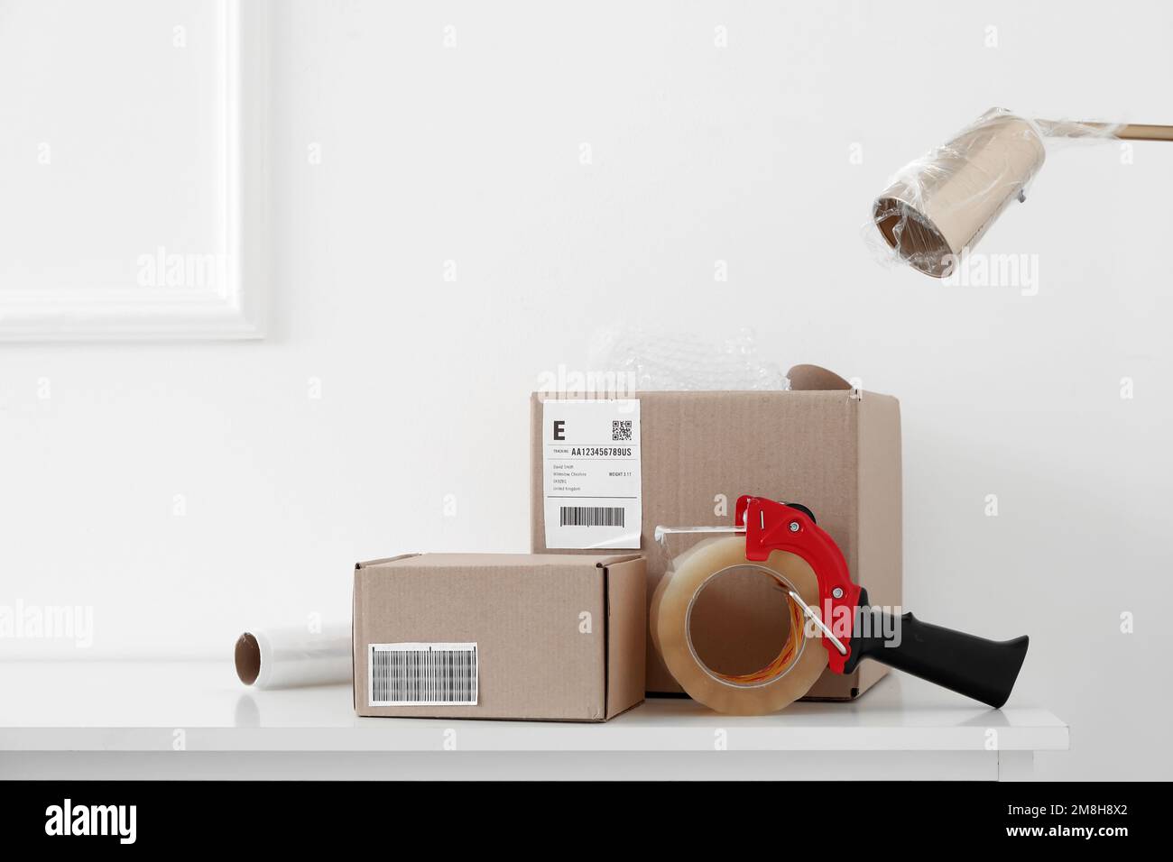 Cardboard boxes with adhesive tape on shelf near light wall Stock Photo ...