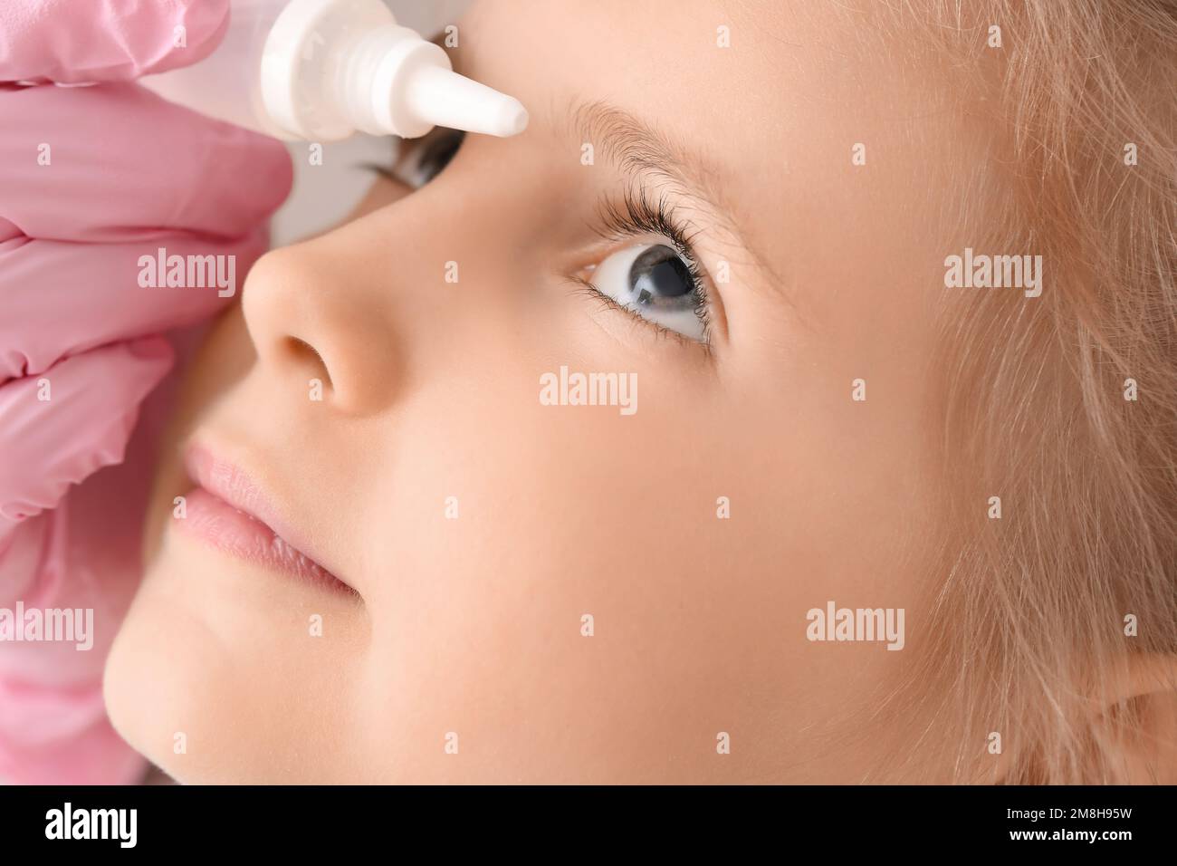 Ophthalmologist putting drops into little girl's eye in clinic, closeup ...