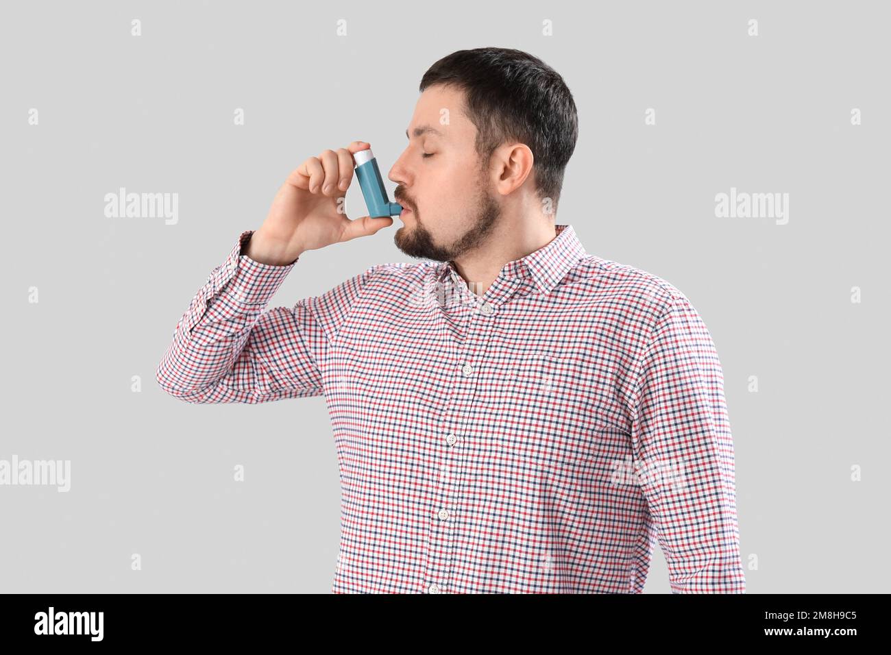 Sick man with inhaler on light background Stock Photo - Alamy