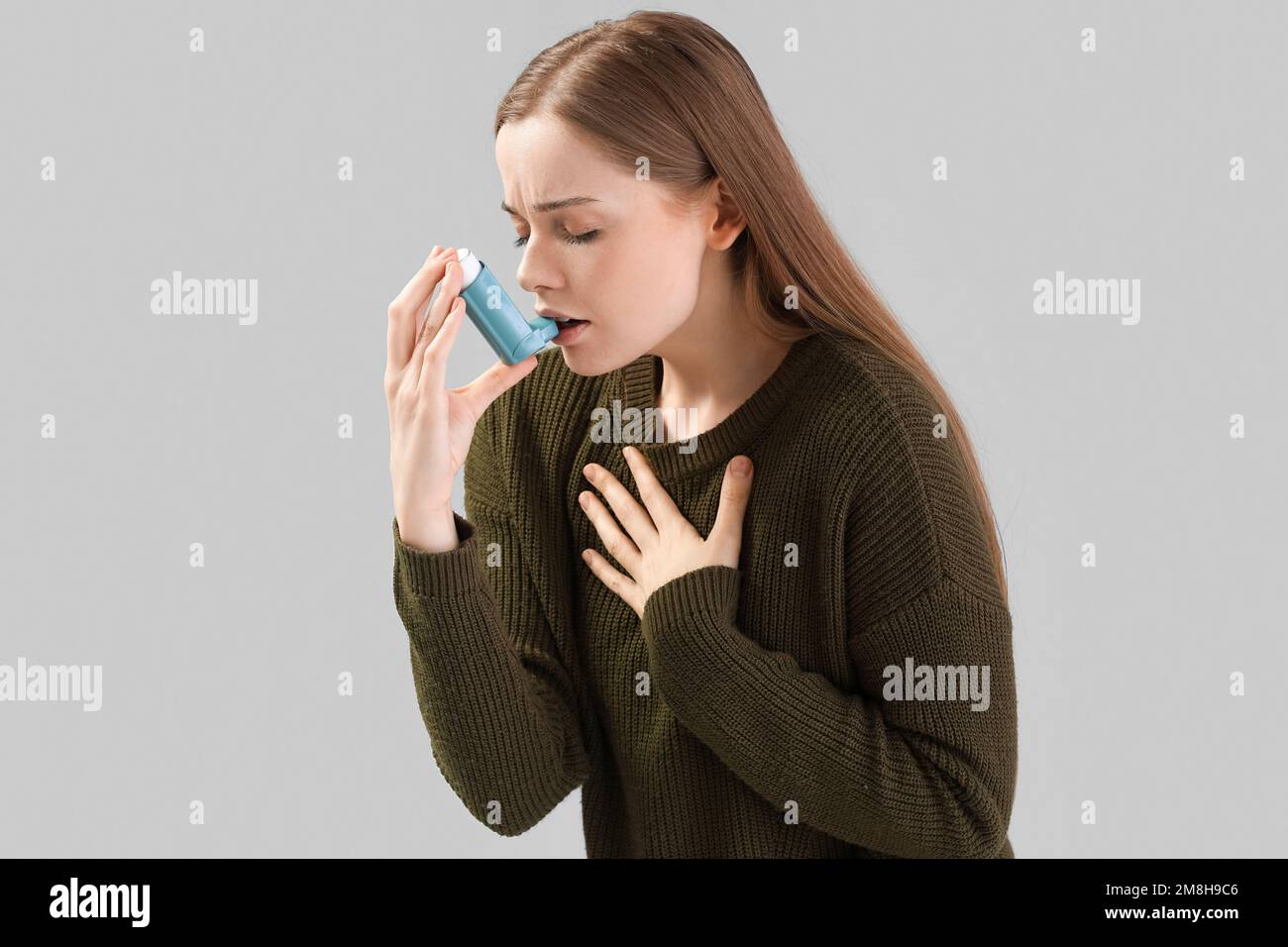 Sick young woman with inhaler on grey background Stock Photo - Alamy