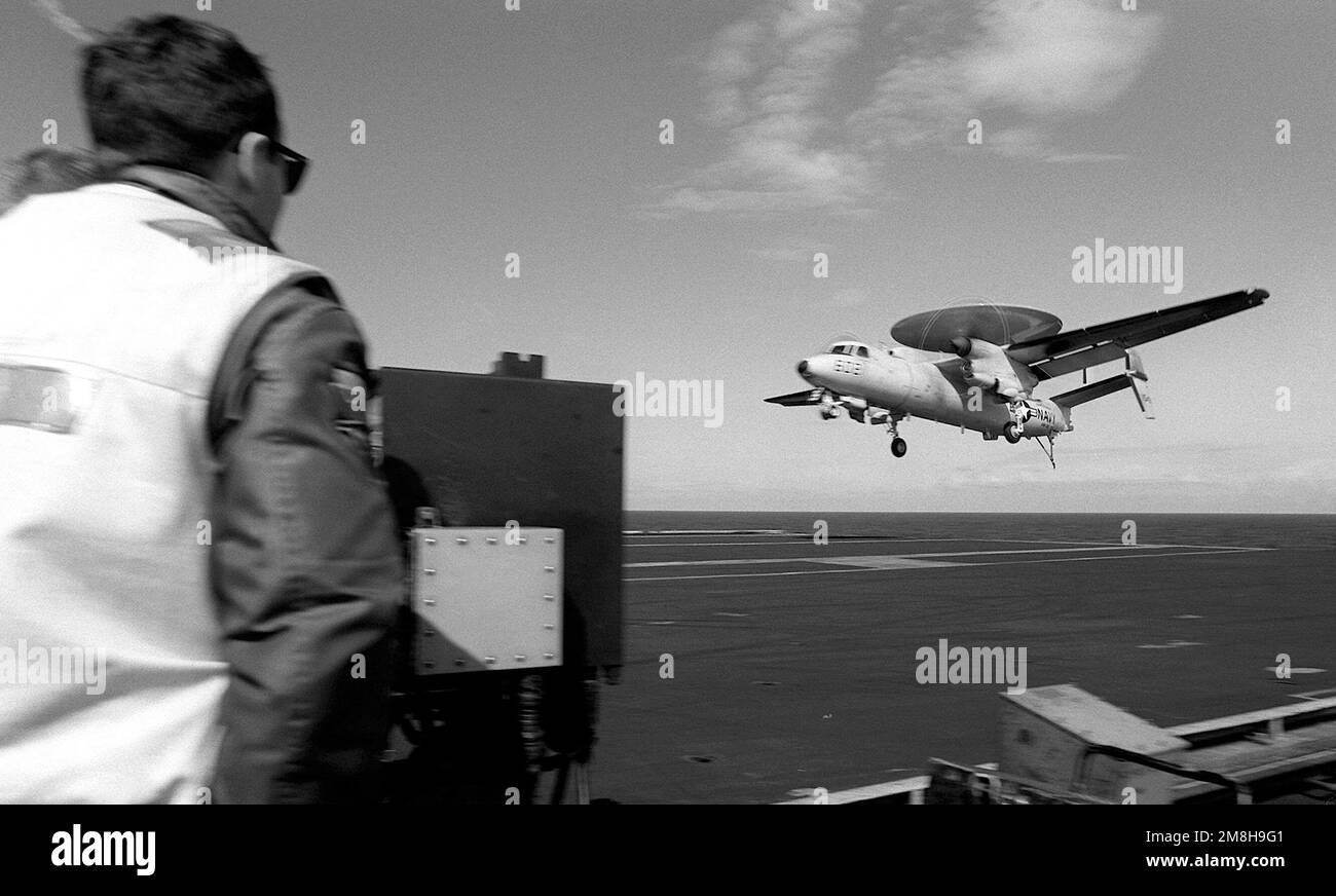 A landing signal officer watches as an E-2C Hawkeye aircraft prepares ...