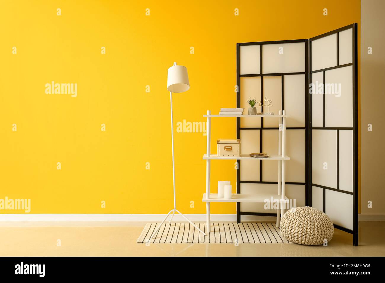 Interior of room with folding screen, shelving unit and pouf near ...
