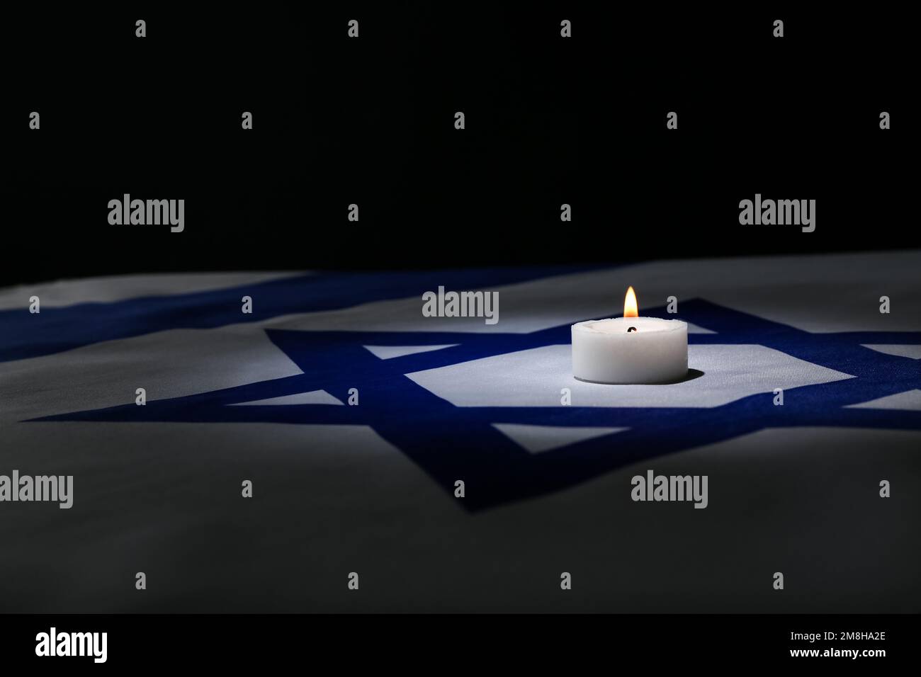 Burning candle on flag of Israel against dark background with space for ...