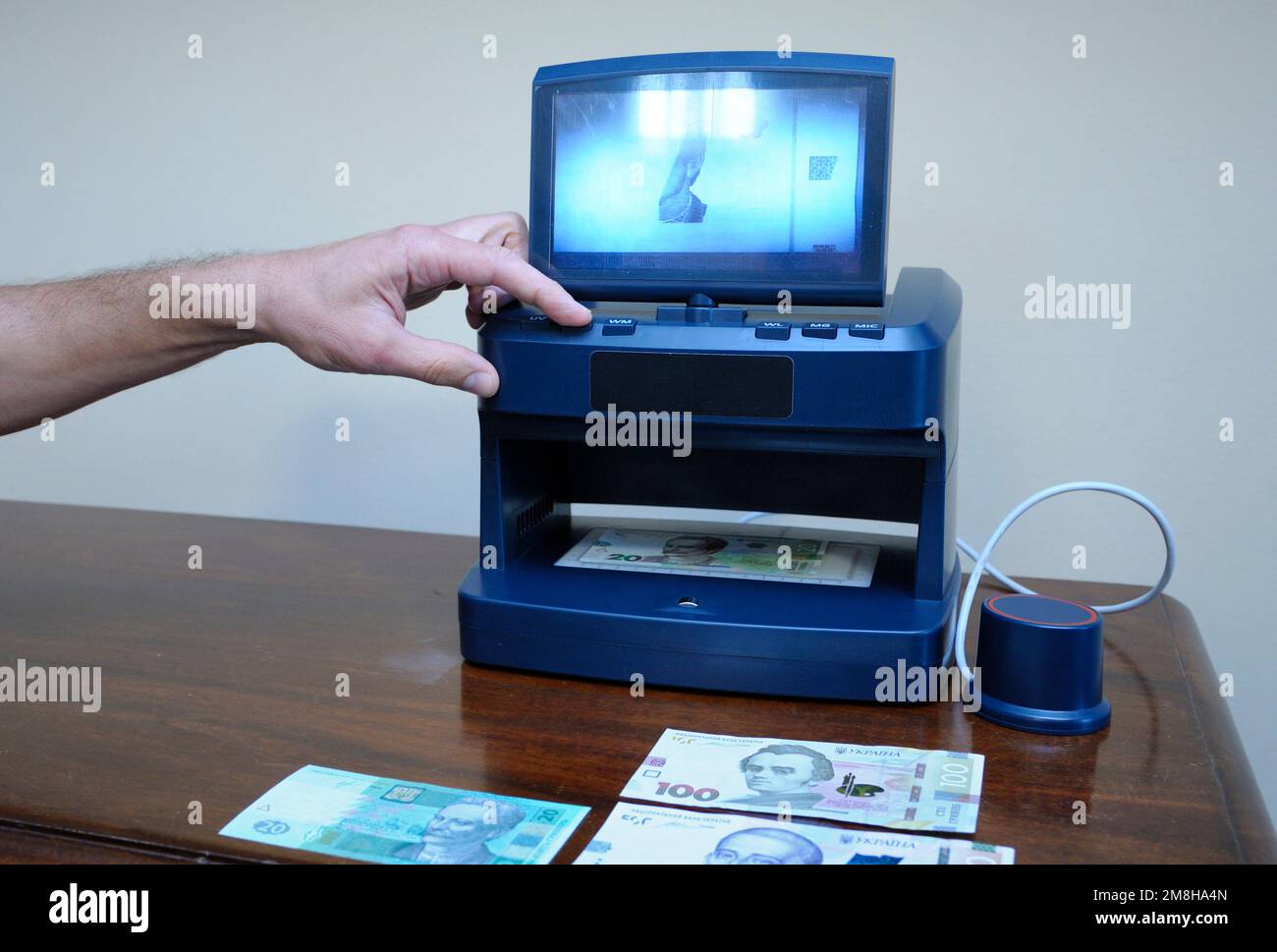Man hand switching money detector on, banknote placed in receiver. Kyiv ...