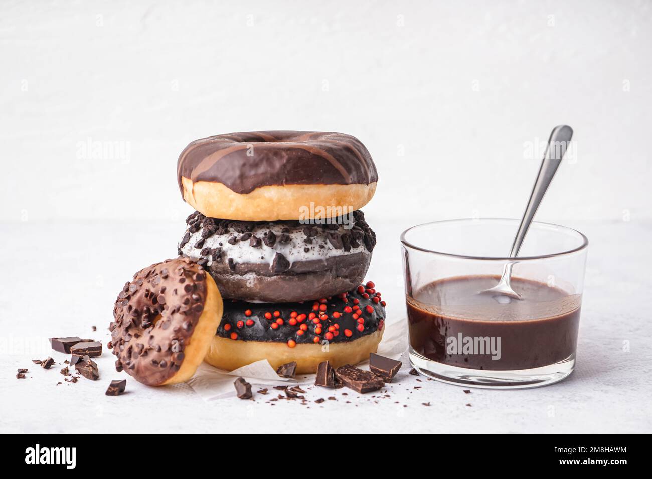 Delicious chocolate donuts and glass of pudding on white table Stock ...
