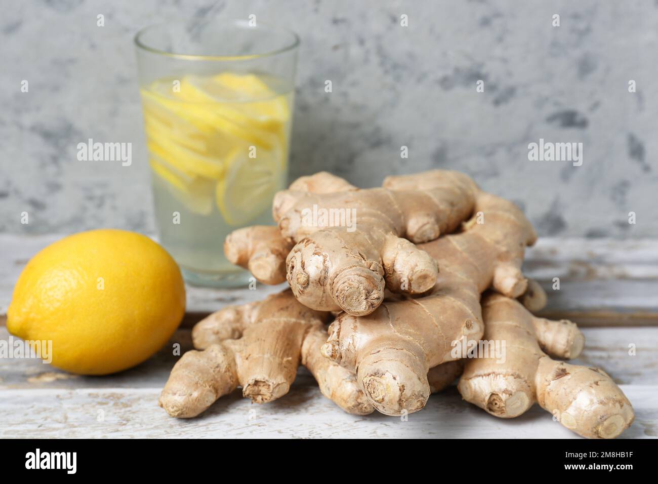 Fresh ginger roots, glass of water and lemon on wooden table Stock ...