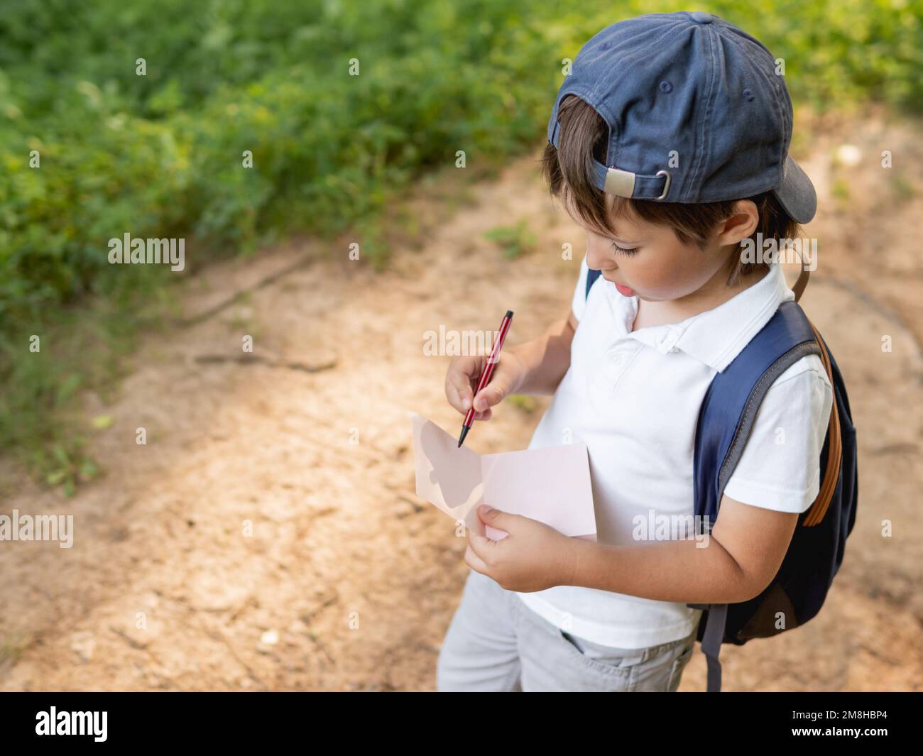 Mindful boy writes something in notebook while walking in forest ...