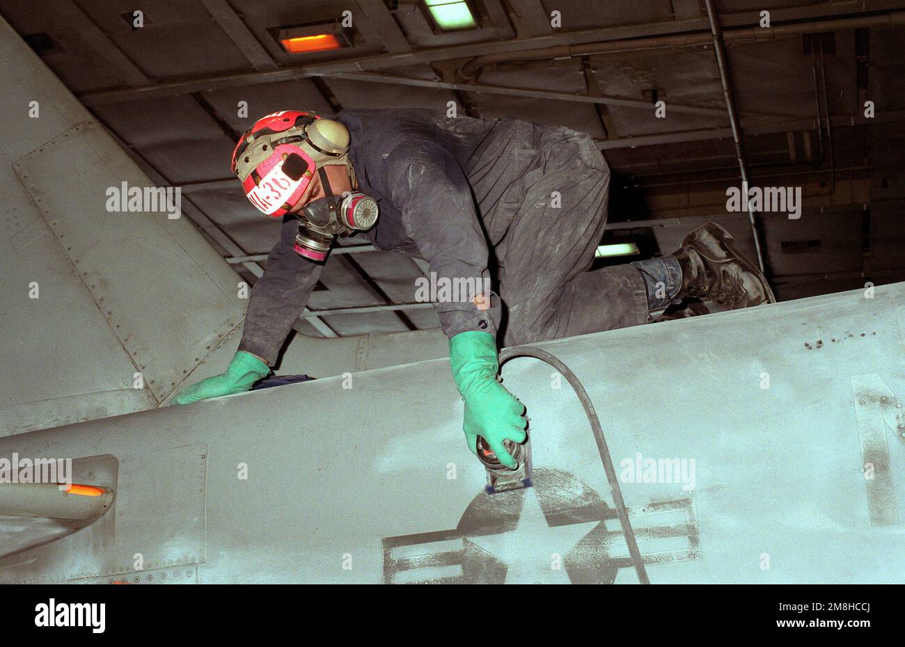 A member of Attack Squadron 36 (VA-36) sands part of the fuselage of an ...