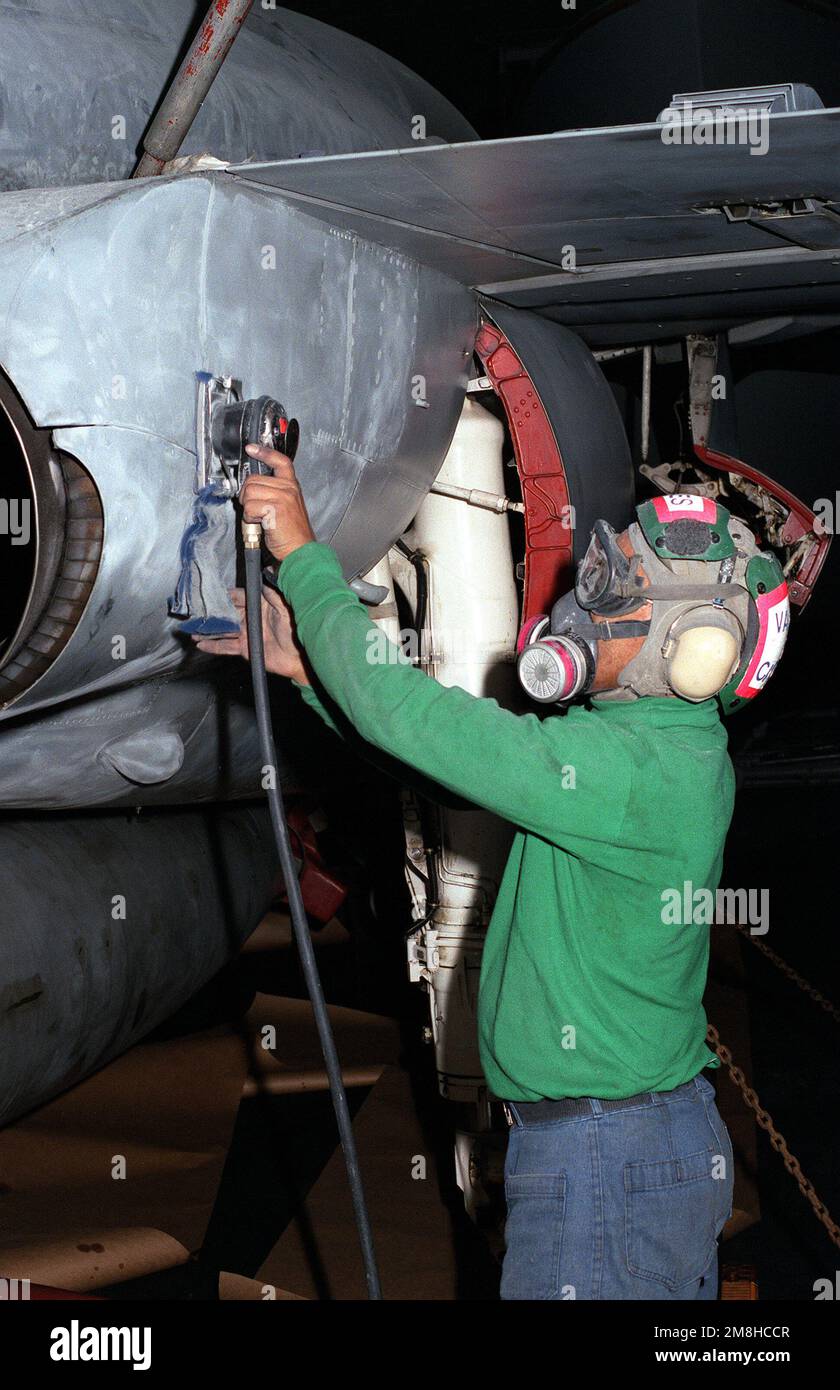 A member of Attack Squadron 36 (VA-36) sands part of the fuselage of an ...