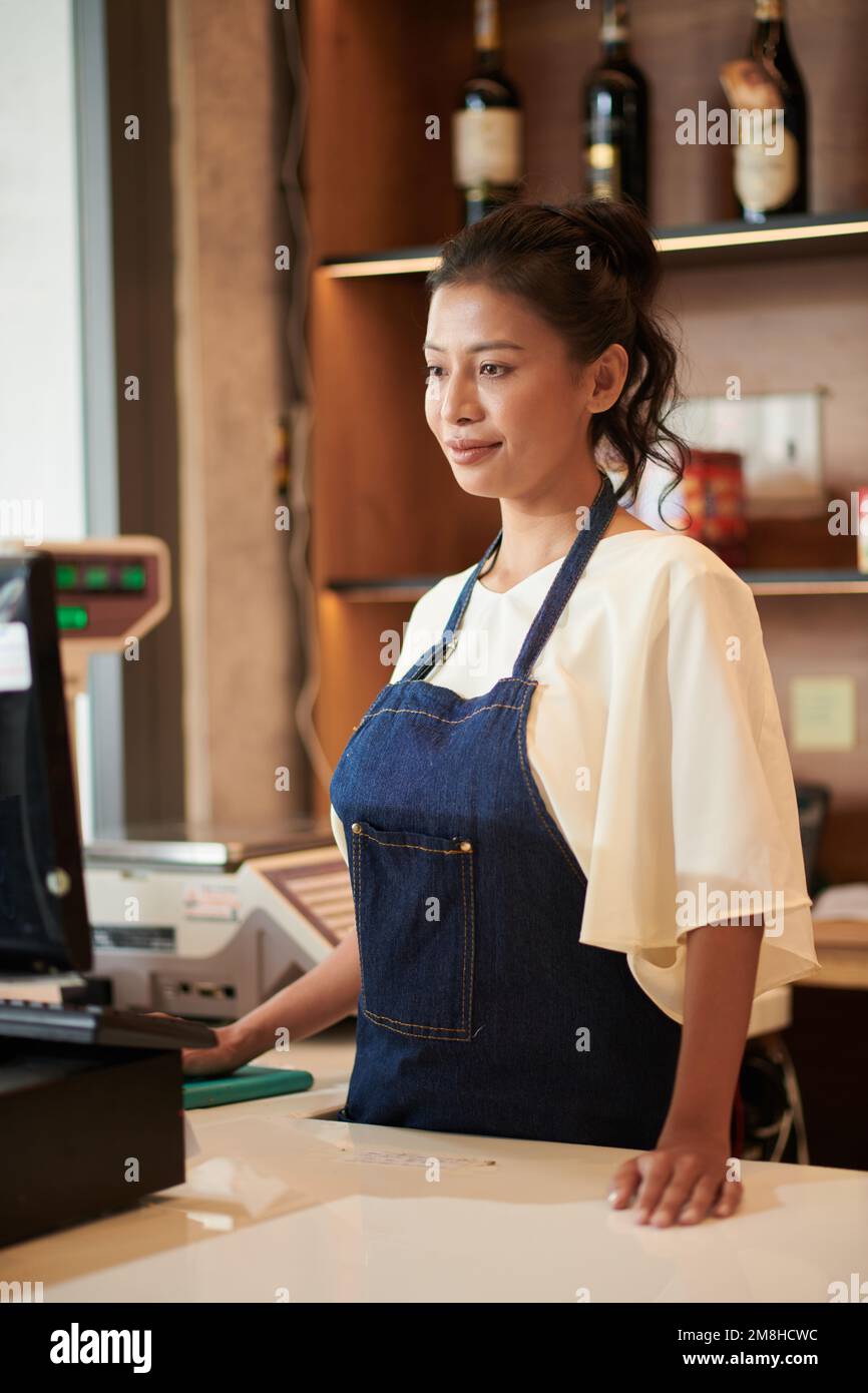 Woman working at cashier desk in grocery store Stock Photo - Alamy