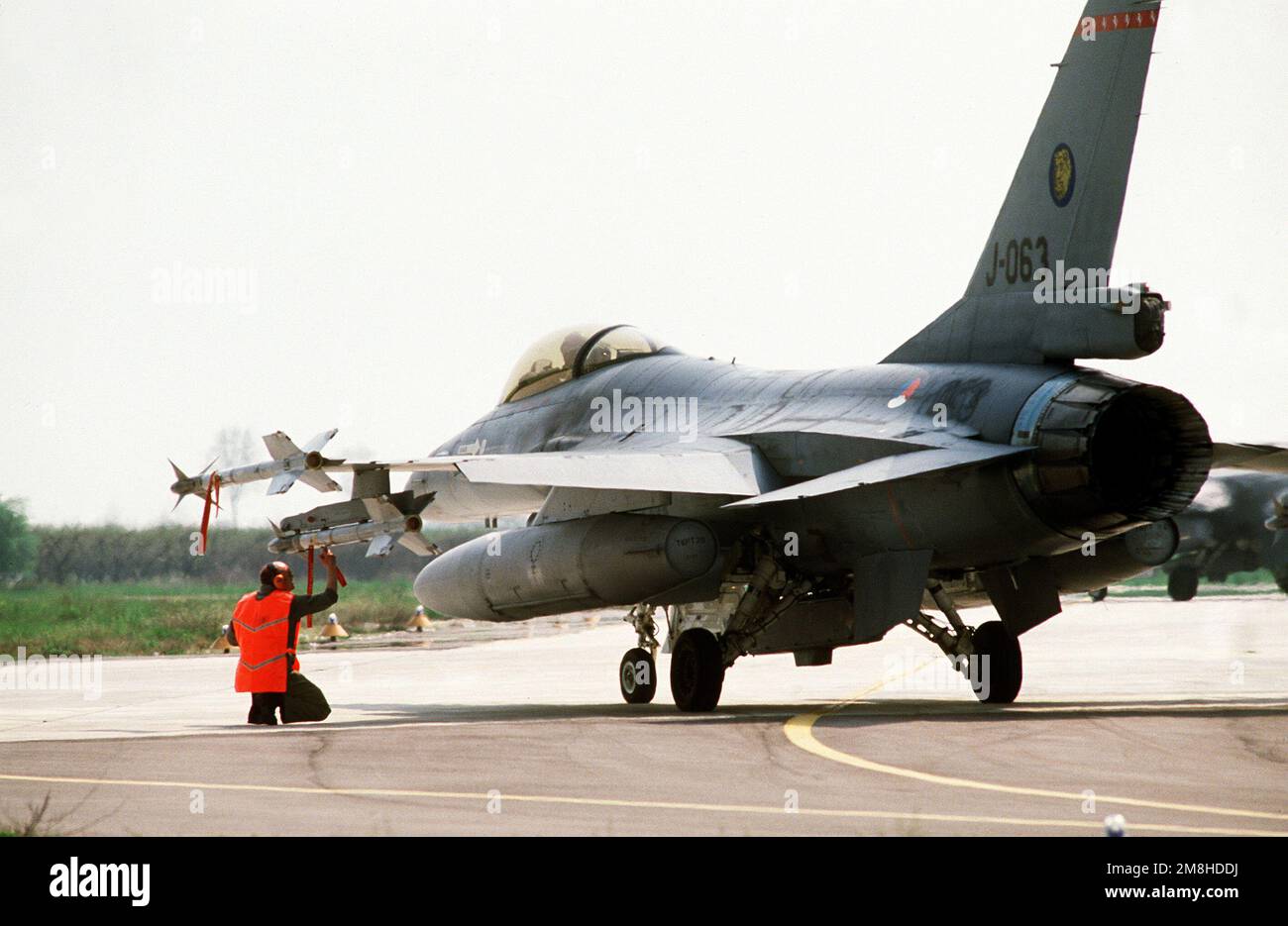 An ordnanceman inspects an AIM-9 Sidewinder missile on the pylon of an ...