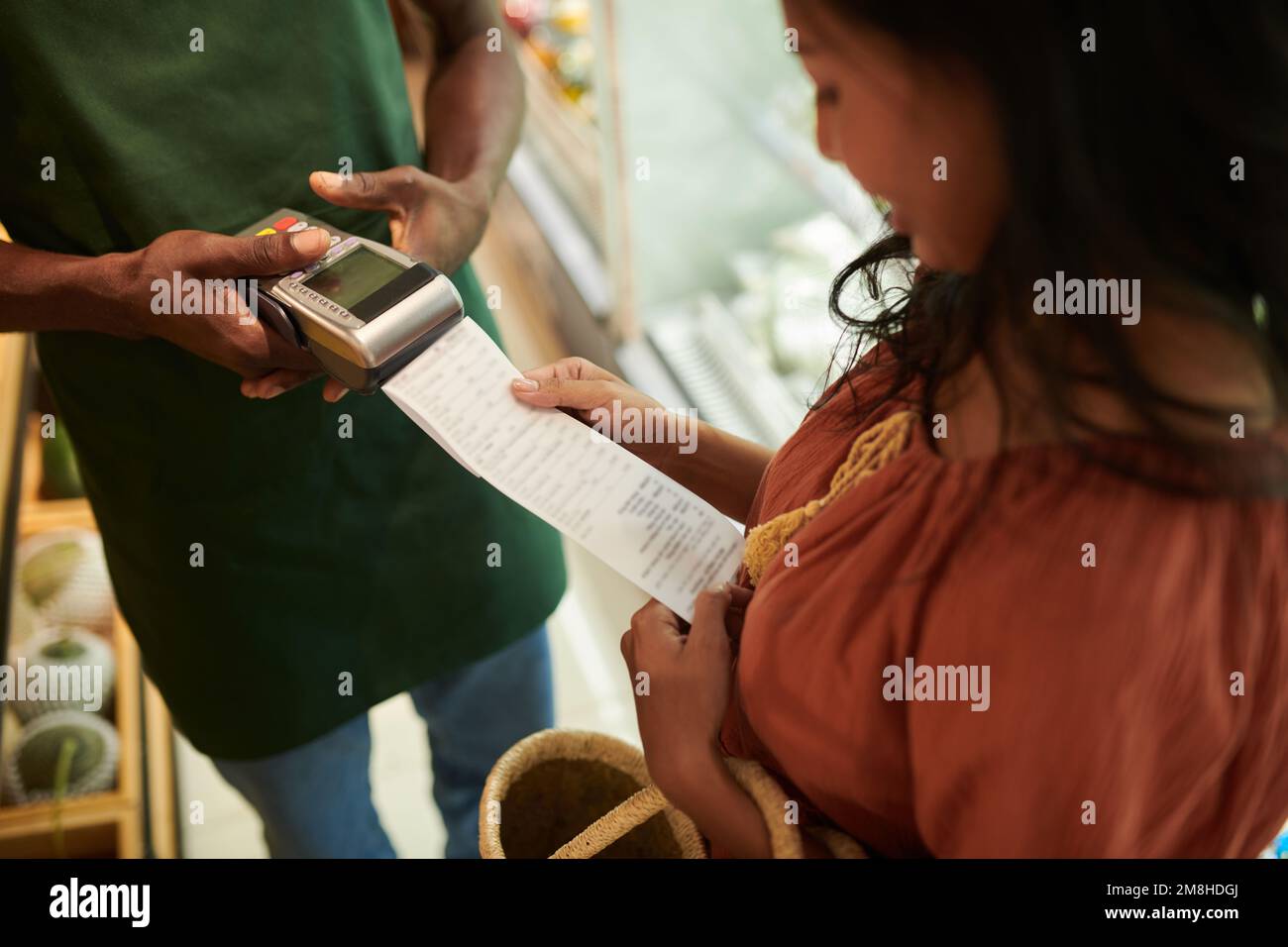Customer taking payment receipt after making purchases in grocery store ...