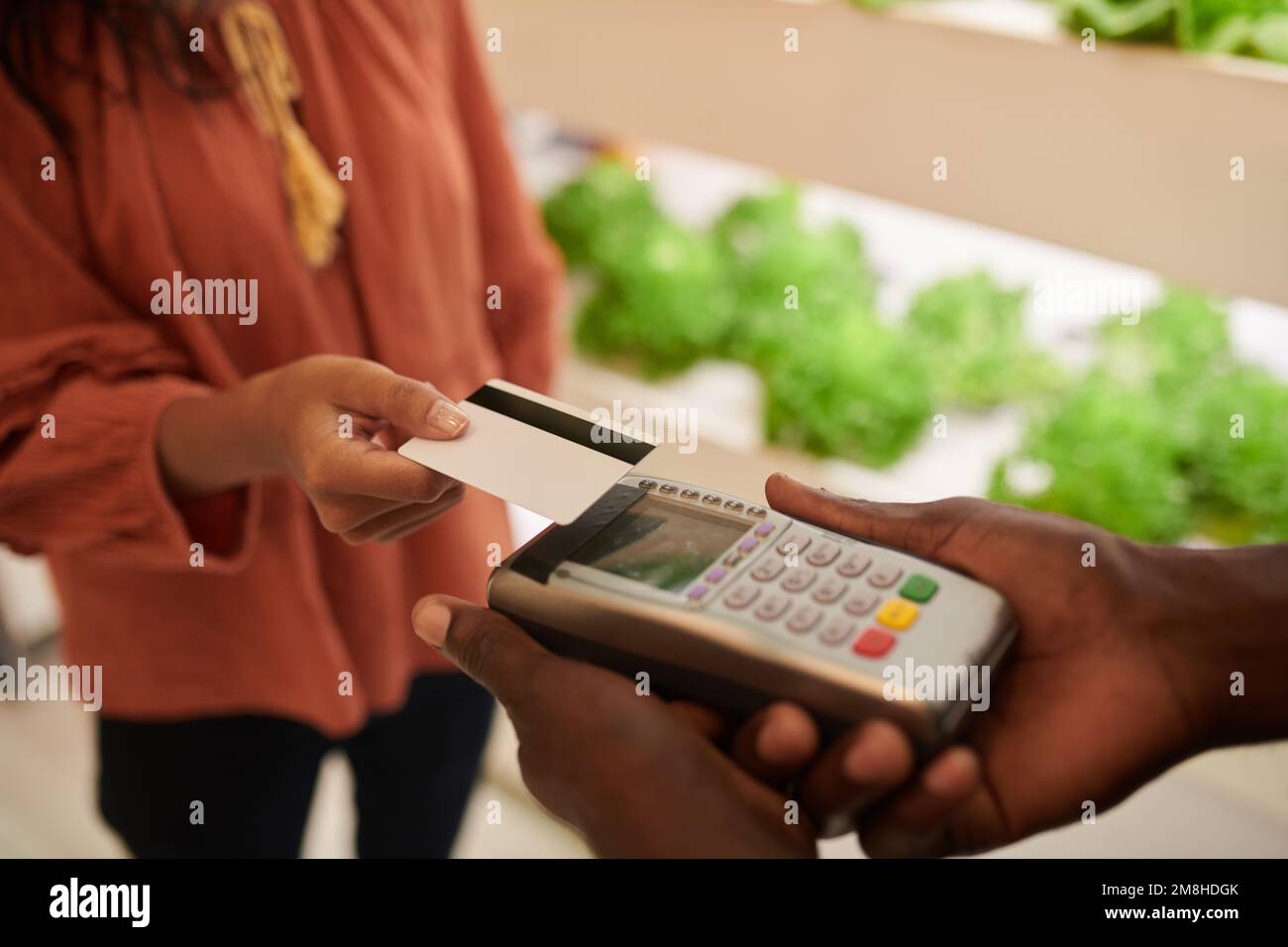 Grocery store customer holding contactless card near card reader to pay ...