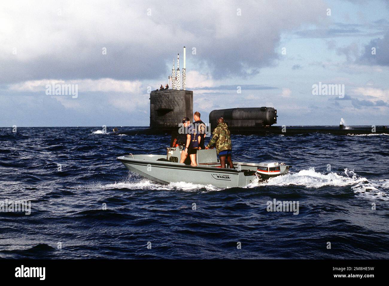 Navy divers approach the nuclear-powered attack submarine USS ...