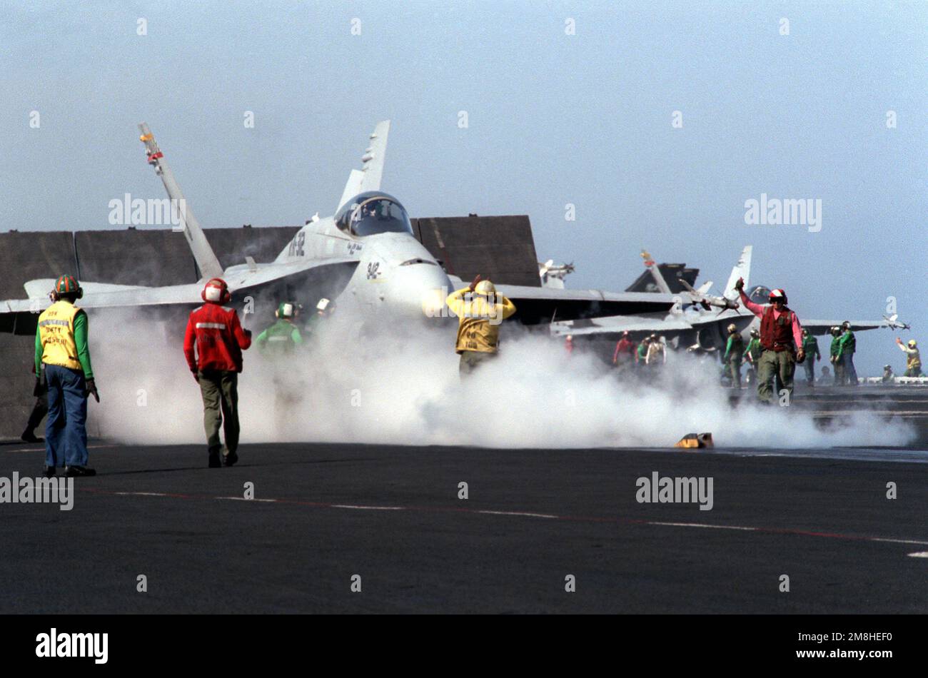 A flight deck crewman directs an F/A-18C Hornet aircraft of Marine ...