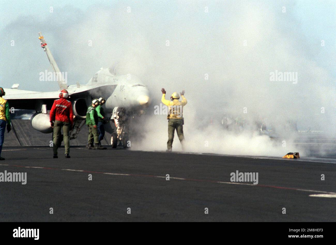 A flight deck crewman directs an F/A-18C Hornet aircraft of Marine ...
