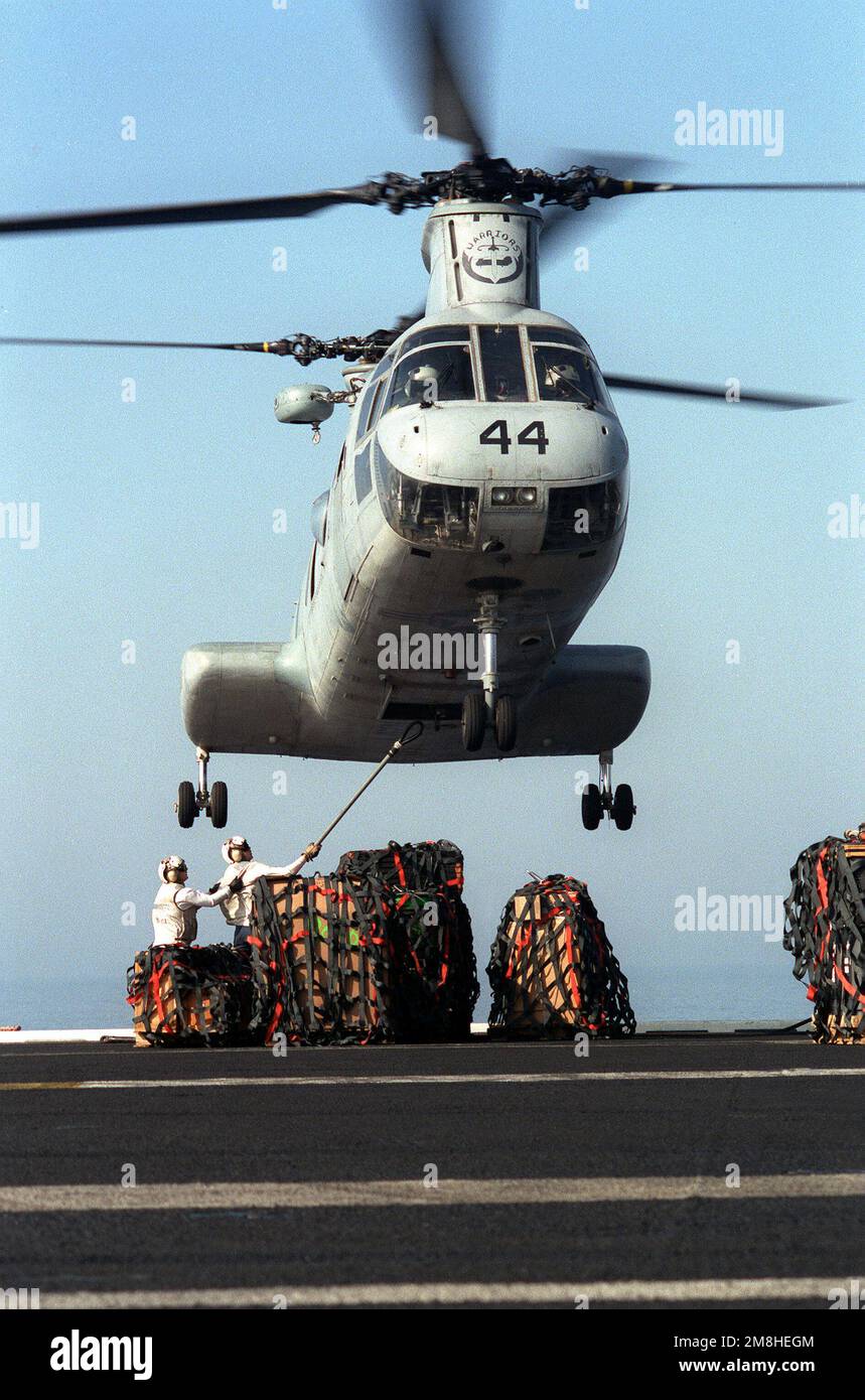 Flight deck crewmen disconnect the cargo sling from the underside of a ...
