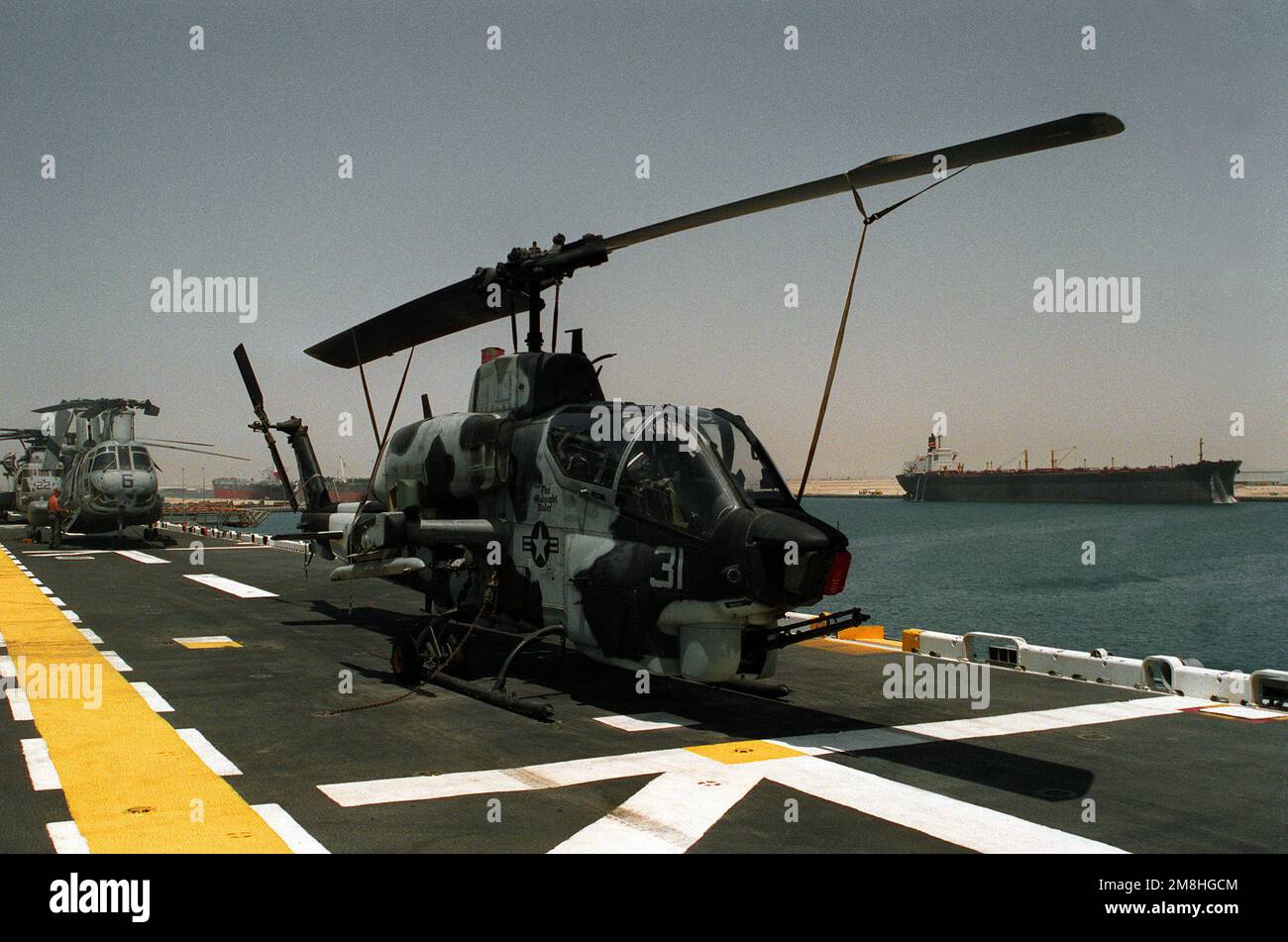 An AH-1W Sea Cobra helicopter stands on the flight deck of the ...
